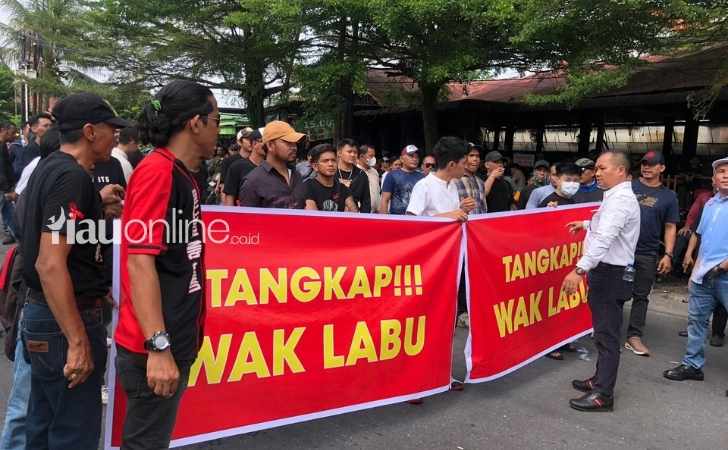 Massa Bentangkan Spanduk Tangkap Wak Labu Saat SF Hariyanto Bersaksi